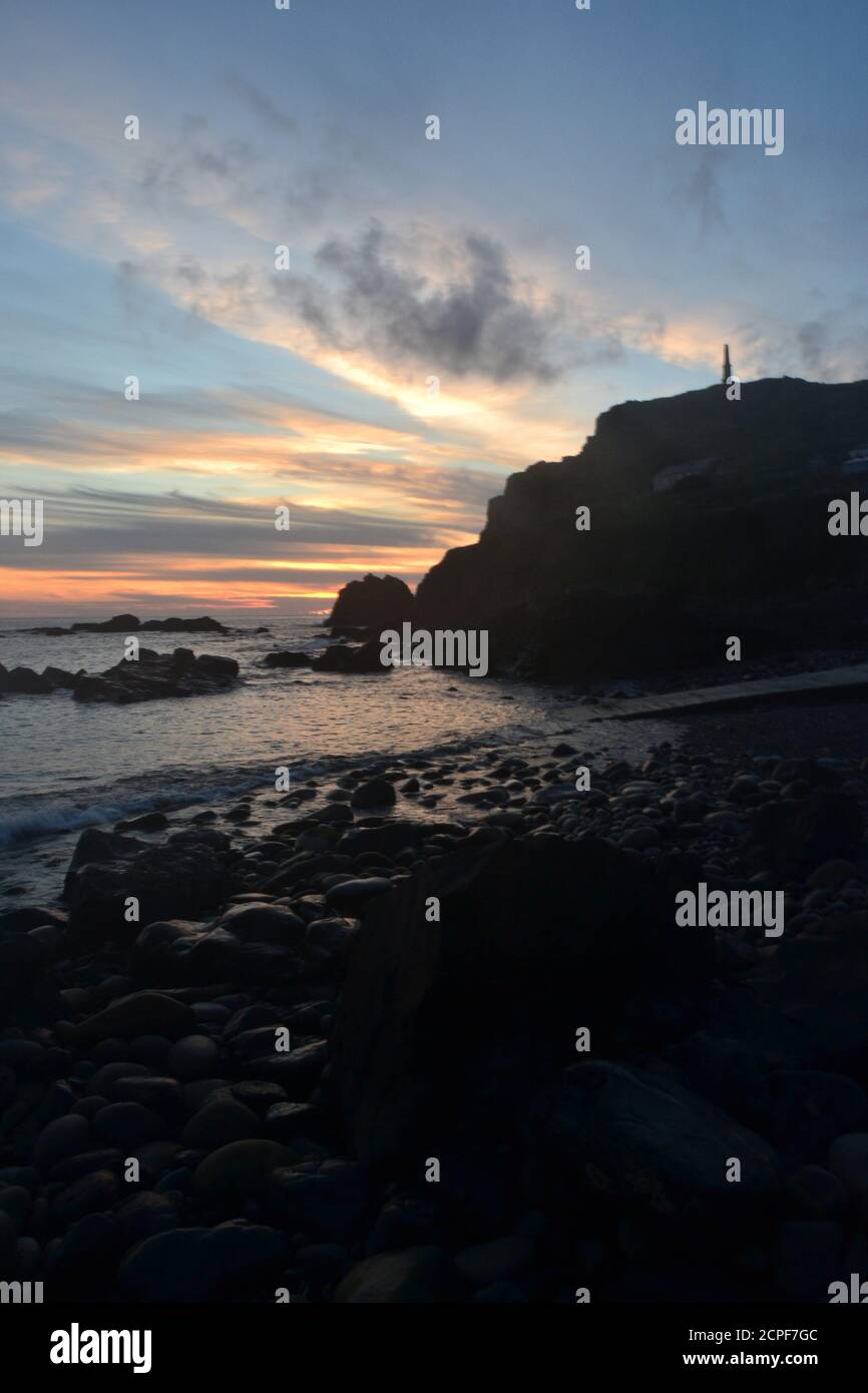The sun setting behind Cape Cornwall, Cornwall, UK with beach in ...