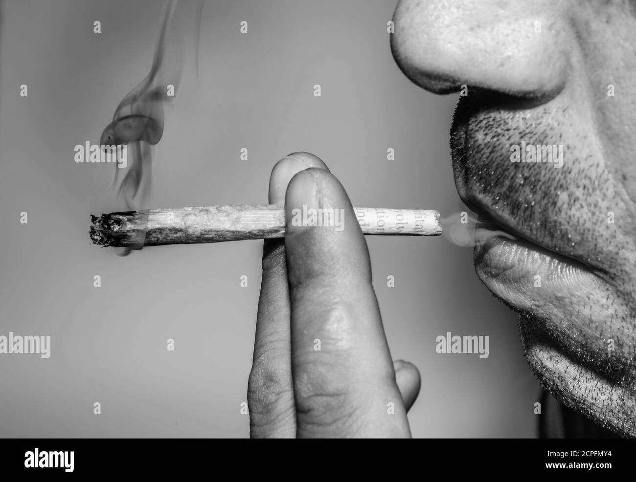 Close up portrait of a Caucasian male rolling and smoking a marijuana ...