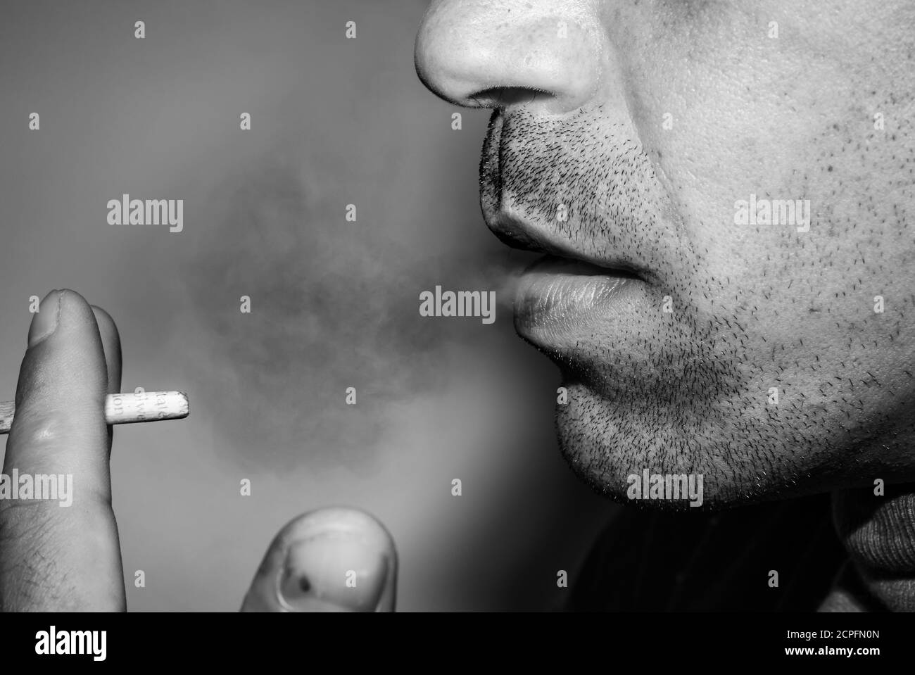 Close up portrait of a Caucasian male rolling and smoking a marijuana ...