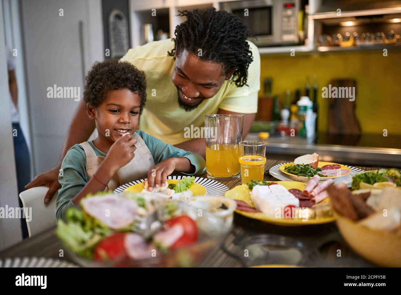 Afro-American male child with dad eating in kitchen Stock Photo - Alamy