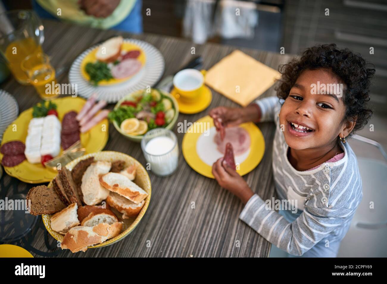 Top view of cheerful female child while eating in kitchen Stock Photo ...