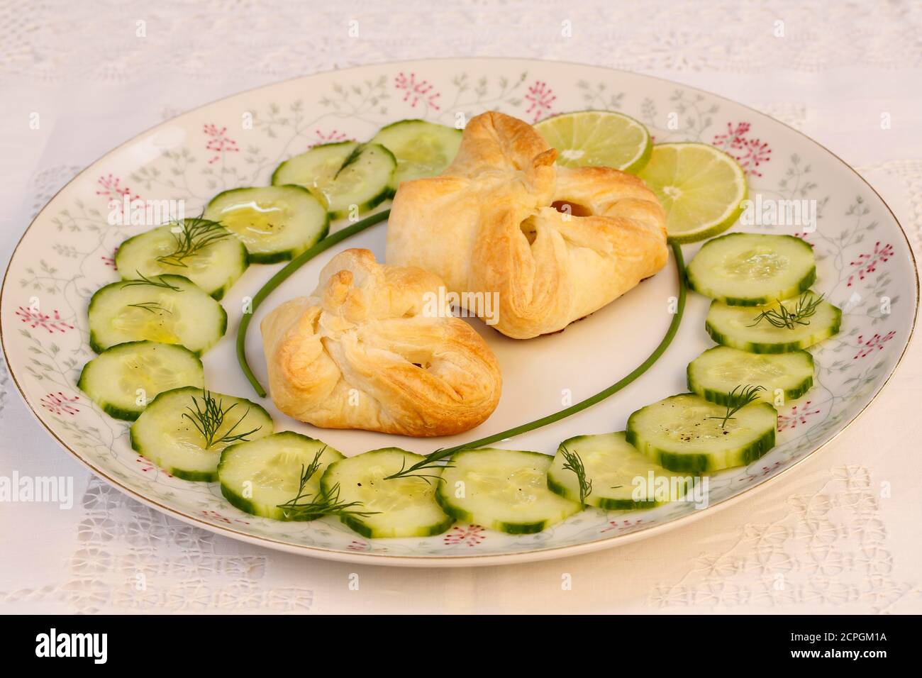Puff pastry pocket enriched with cucumbers and slices of lime on plates ...