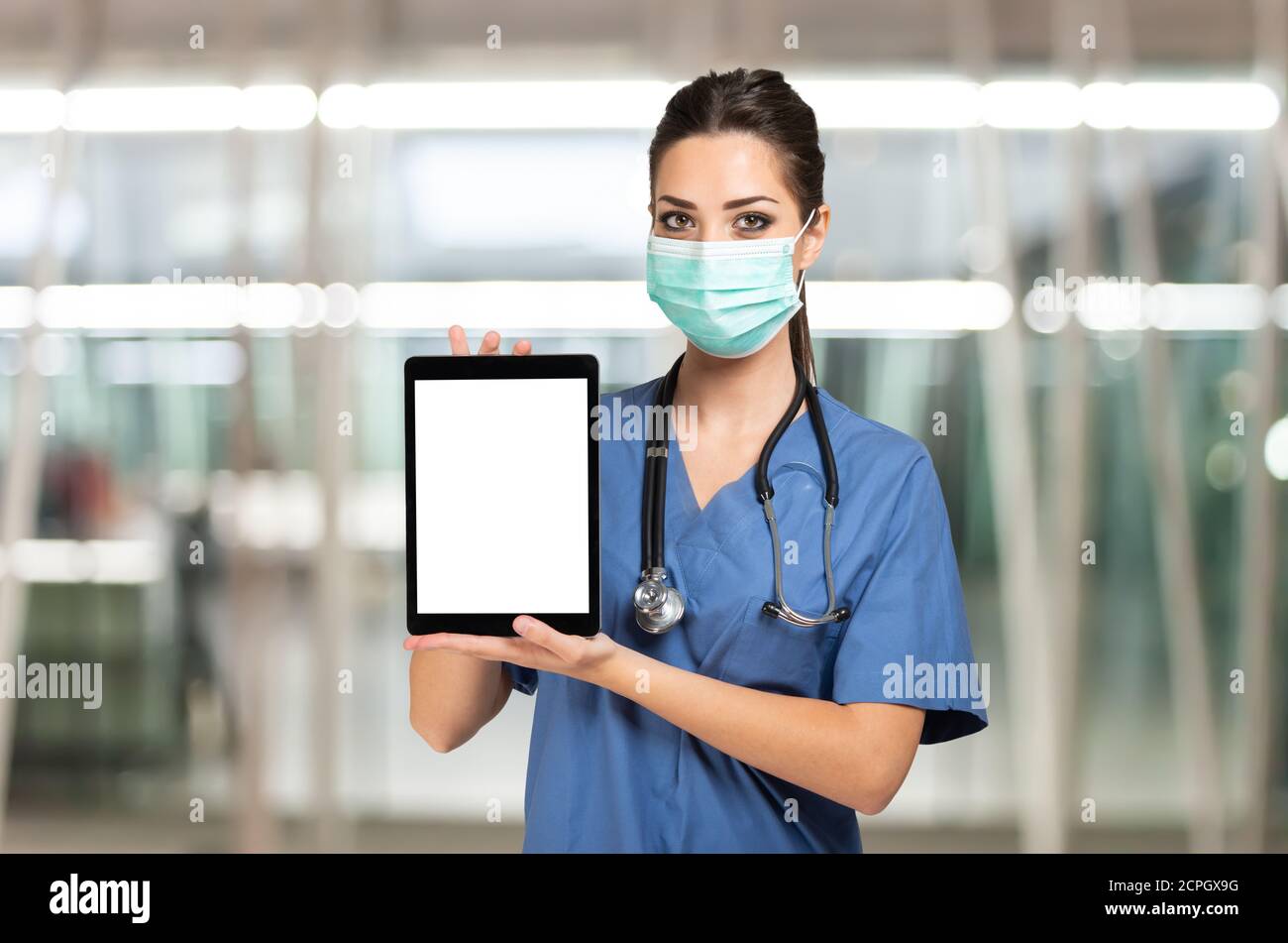 Masked nurse doctor showing a tablet with a white screen Stock Photo ...