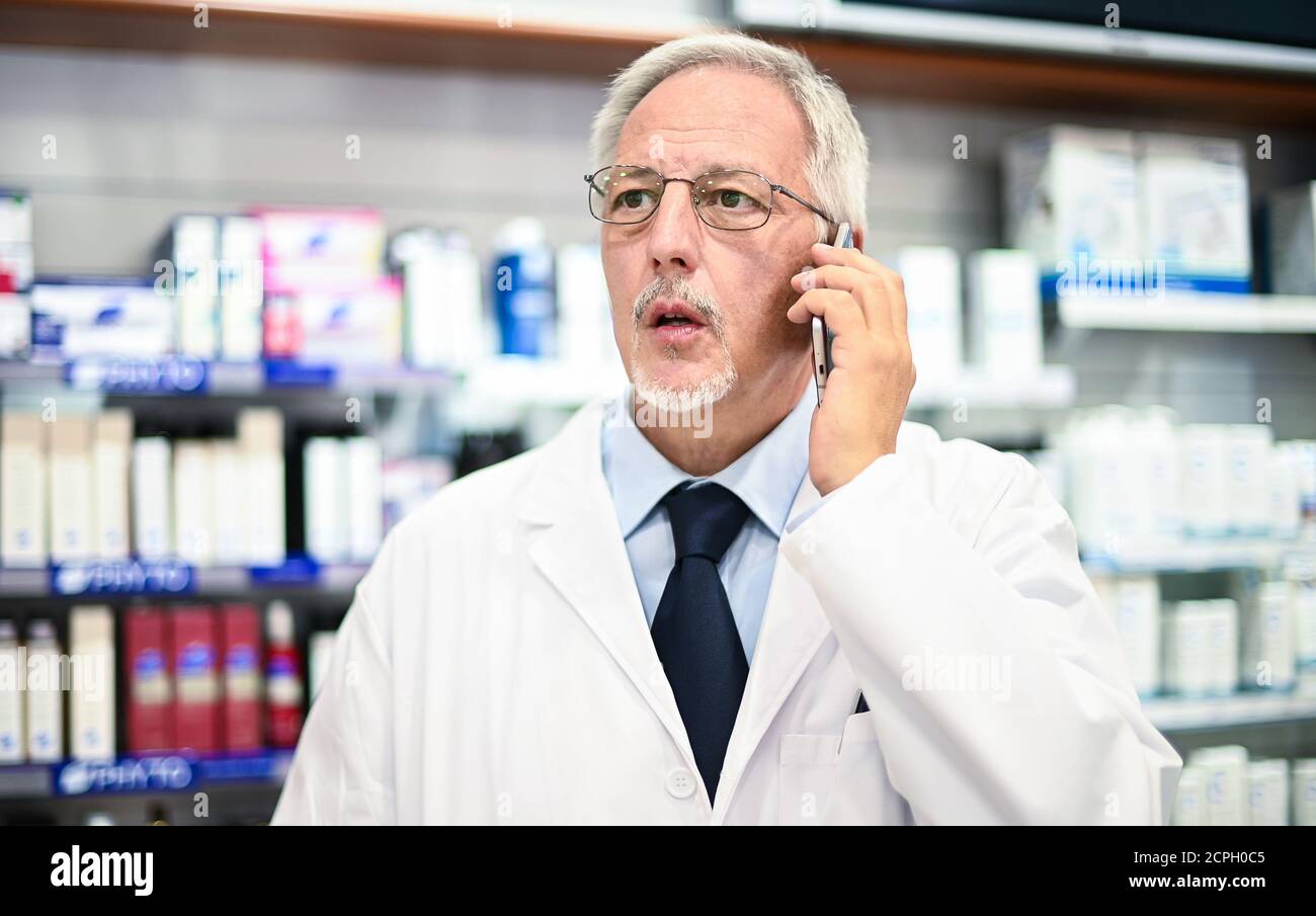 Pharmacist talking on the phone with a customer in his store Stock ...