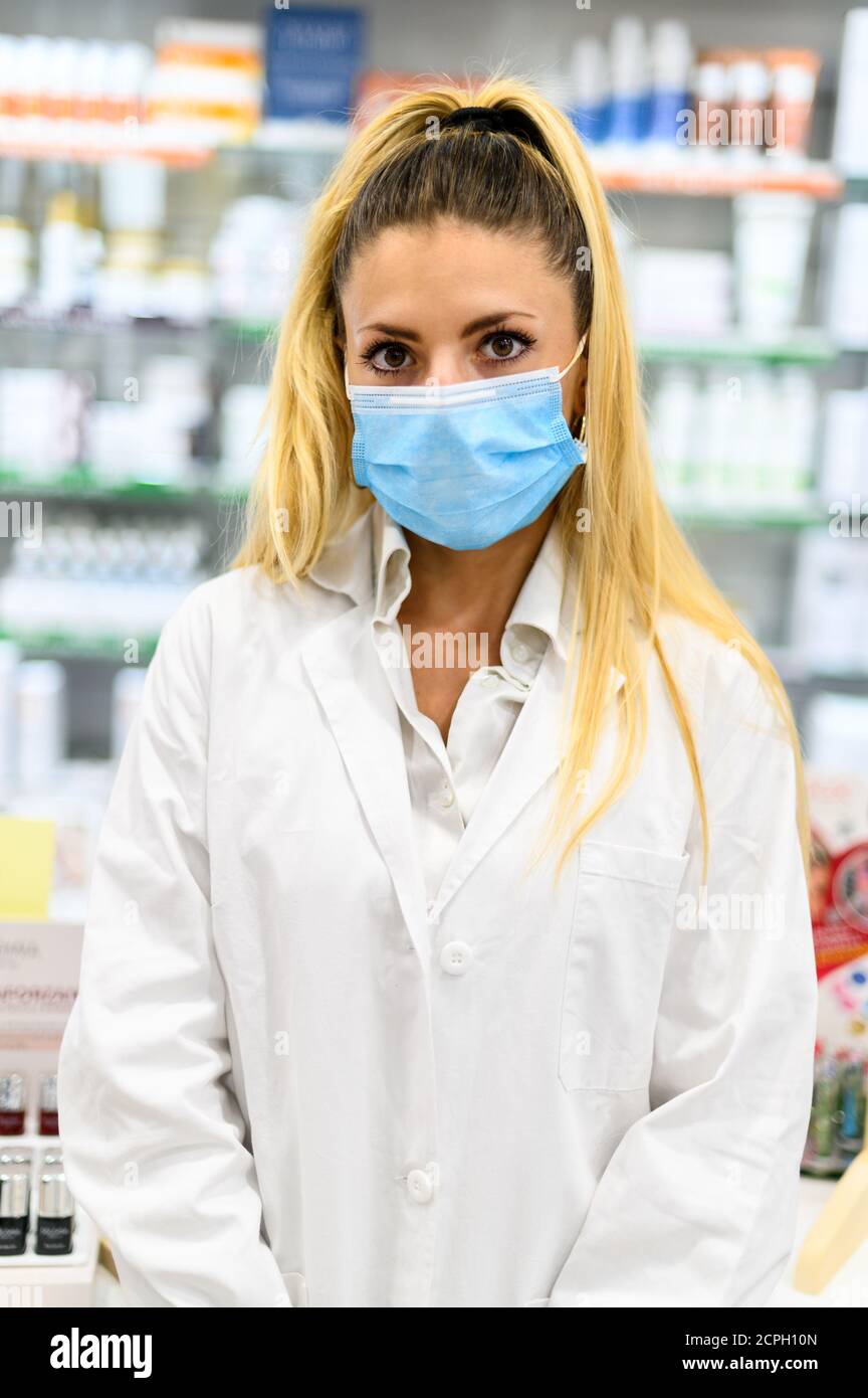 Female pharmacist with protective mask on her face working at pharmacy ...