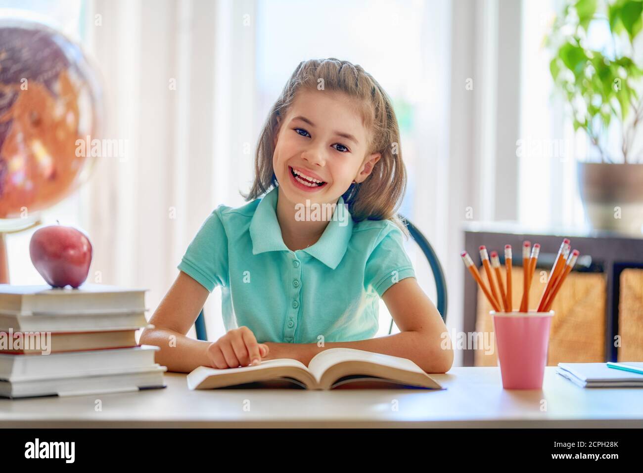 Back to school! Happy cute industrious child is sitting at a desk ...