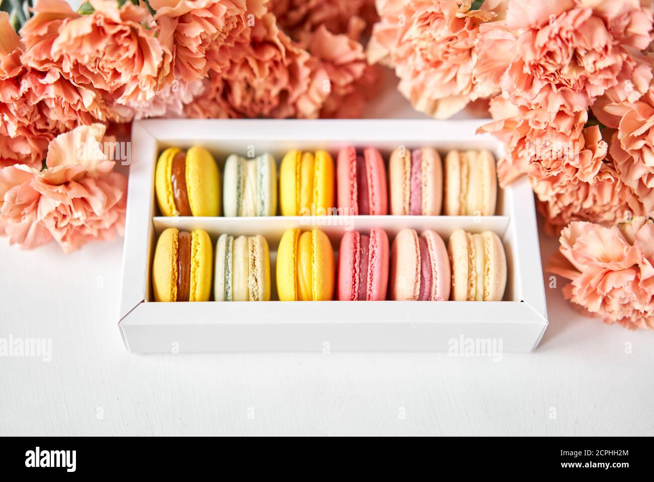 round beautiful sweets macaroni in a festive box with flowers on a ...