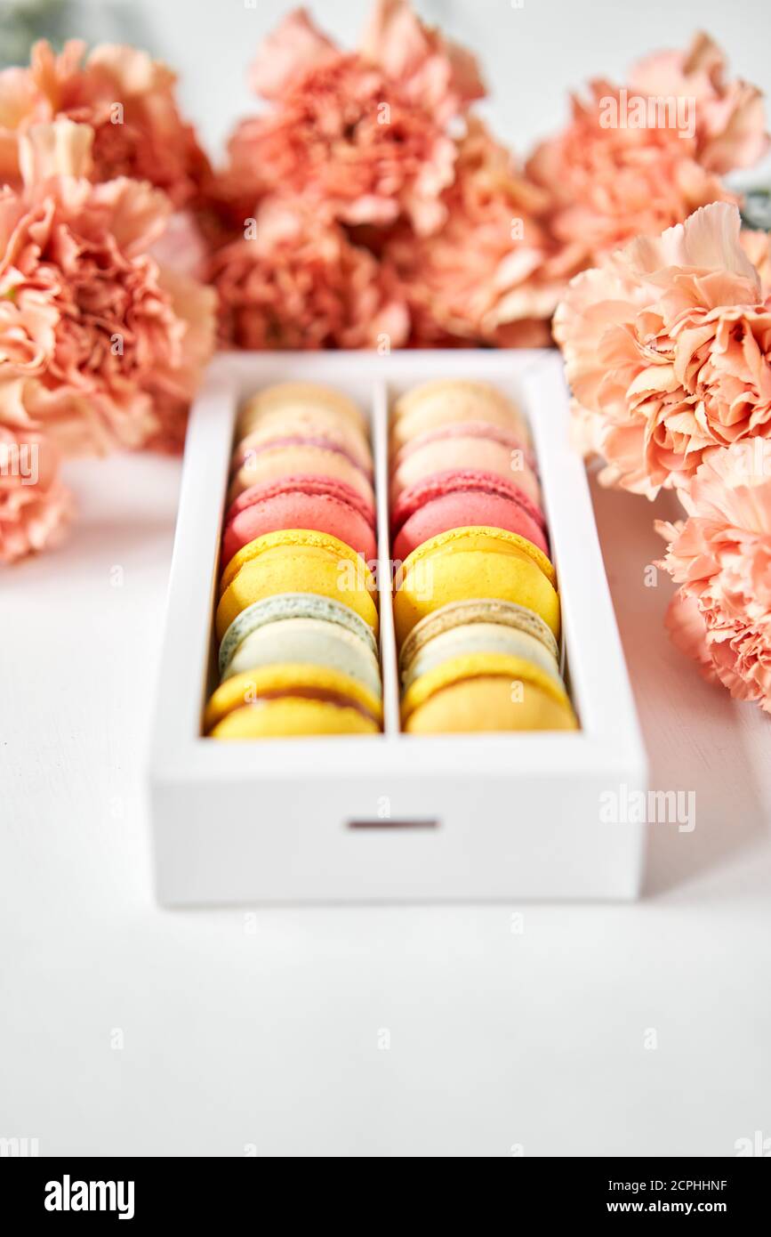 round beautiful sweets macaroni in a festive box with flowers on a ...