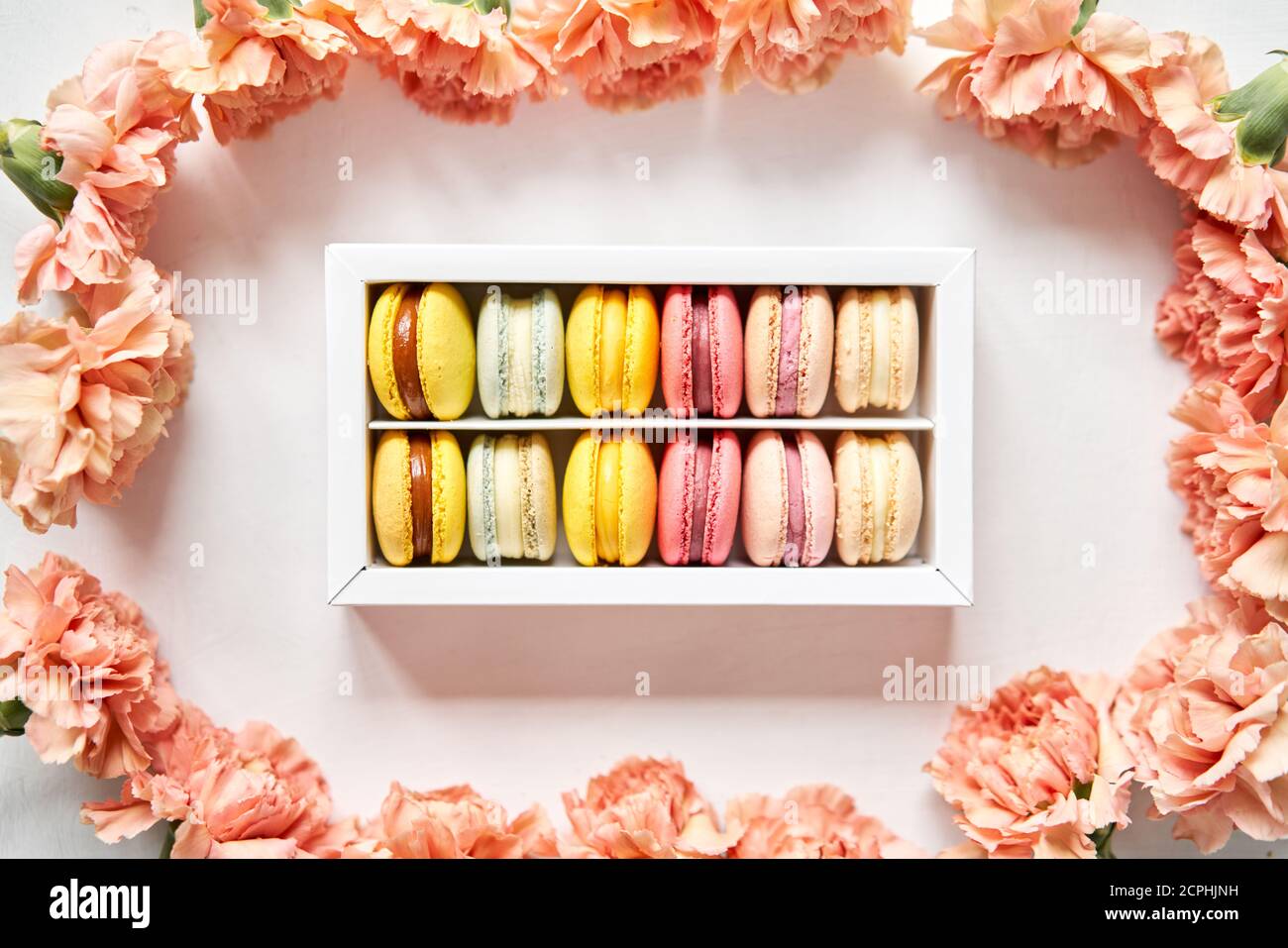 round beautiful sweets macaroni in a festive box with flowers on a ...