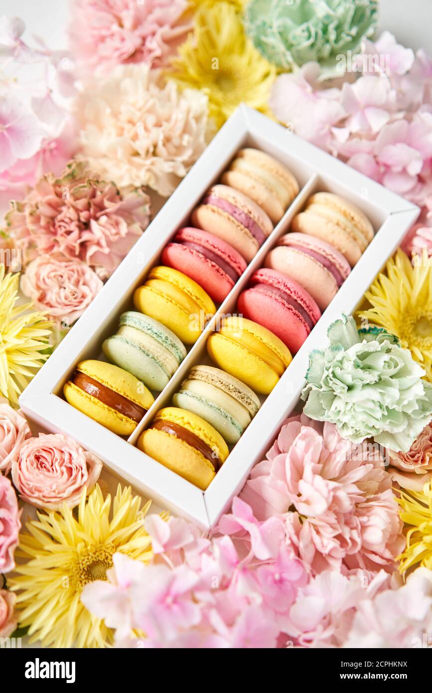 round beautiful sweets macaroni in a festive box with flowers on a ...