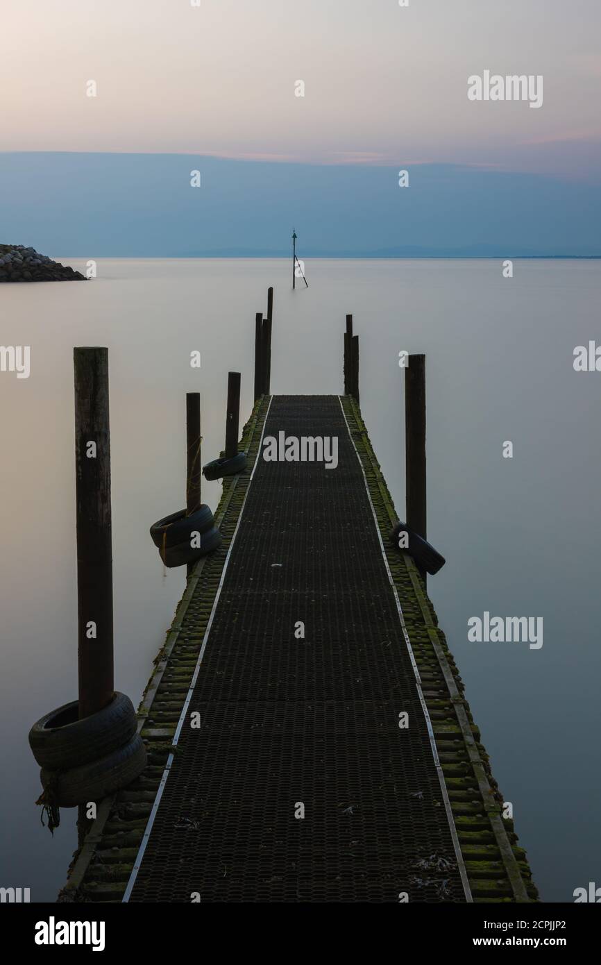 Small jetty in a North Wales harbour. Flat summer sea at dawn in Rhos ...
