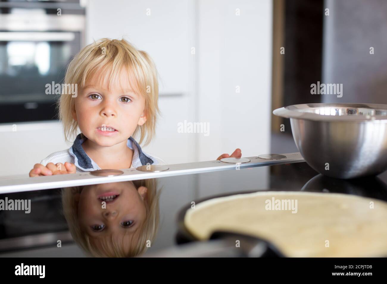 Cute toddler child, blond boy, making pancake in kitchen, eating them ...