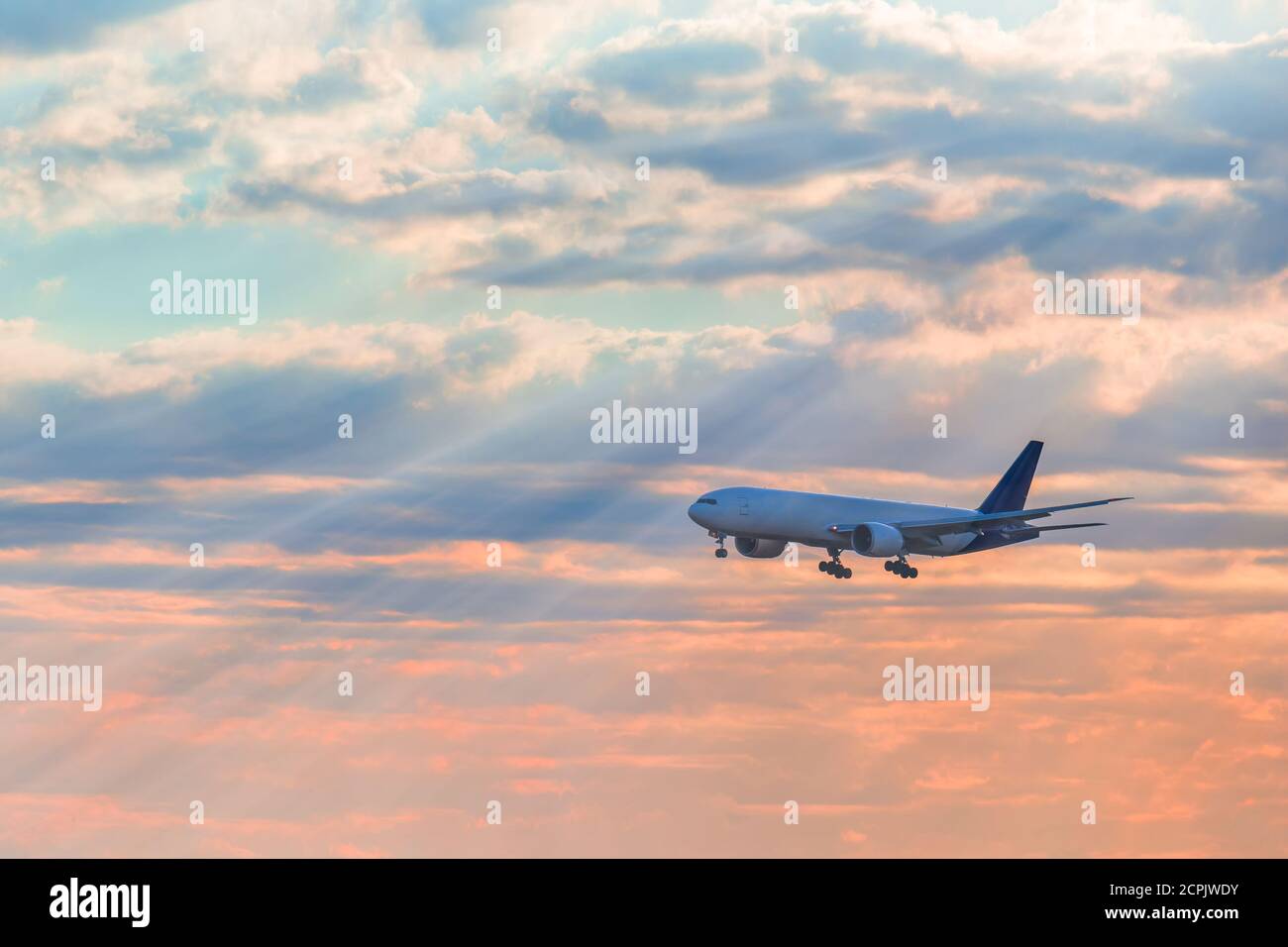 Landing airplane flying on the sky with sunshine and clouds background ...