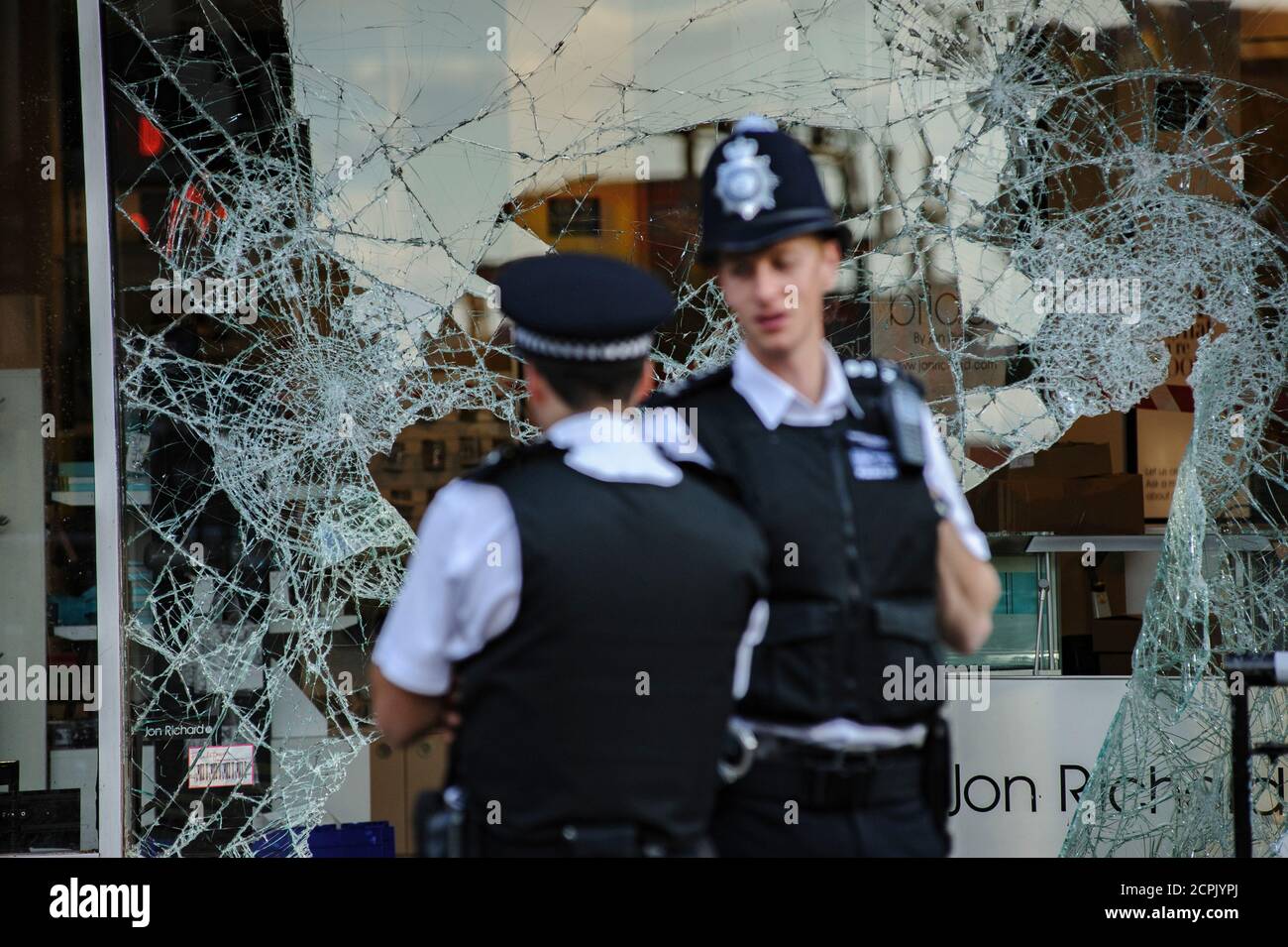 Police guard the smashed and burnt out shops and buildings after London ...
