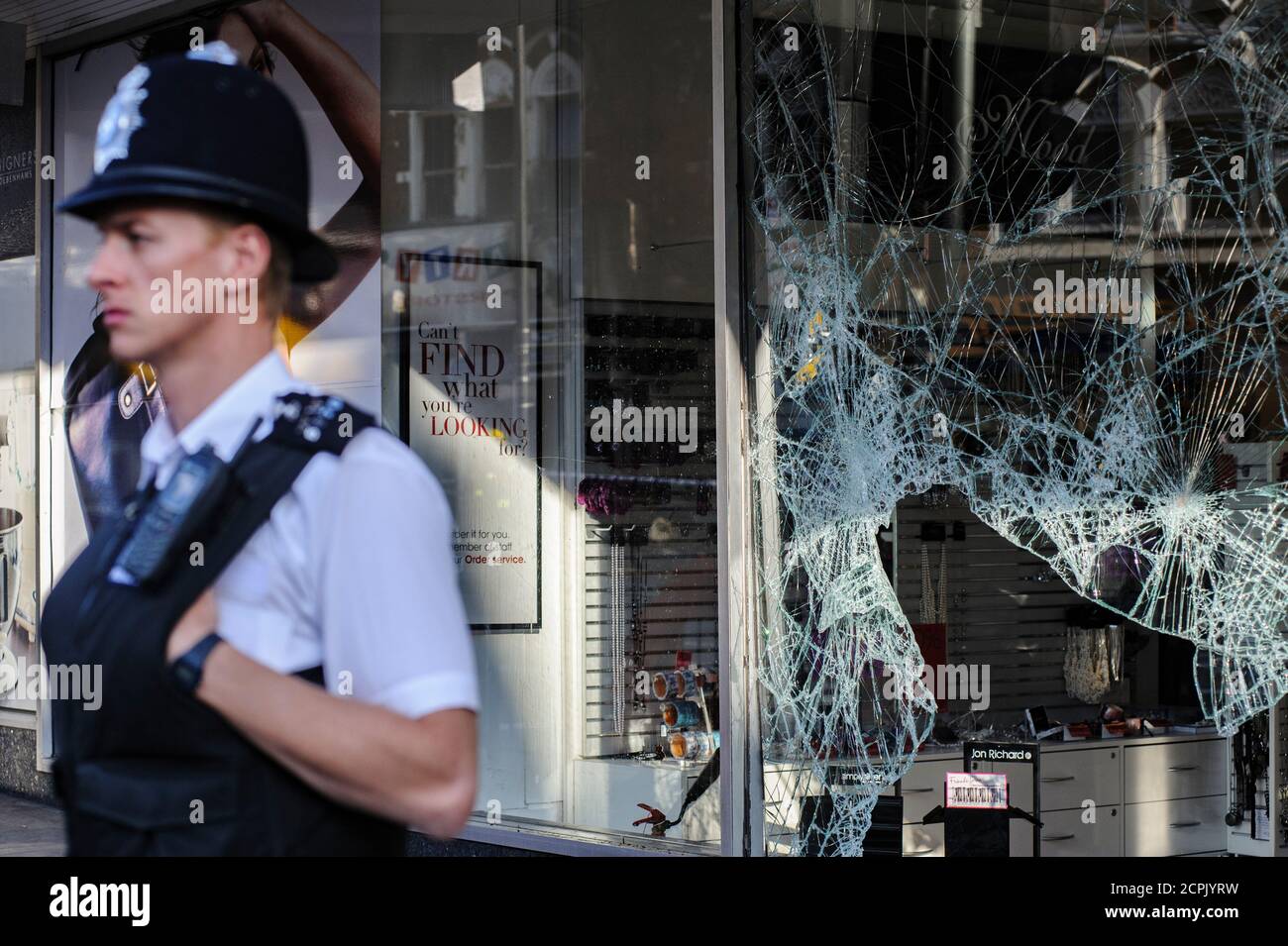 Police guard the smashed and burnt out shops and buildings after London ...
