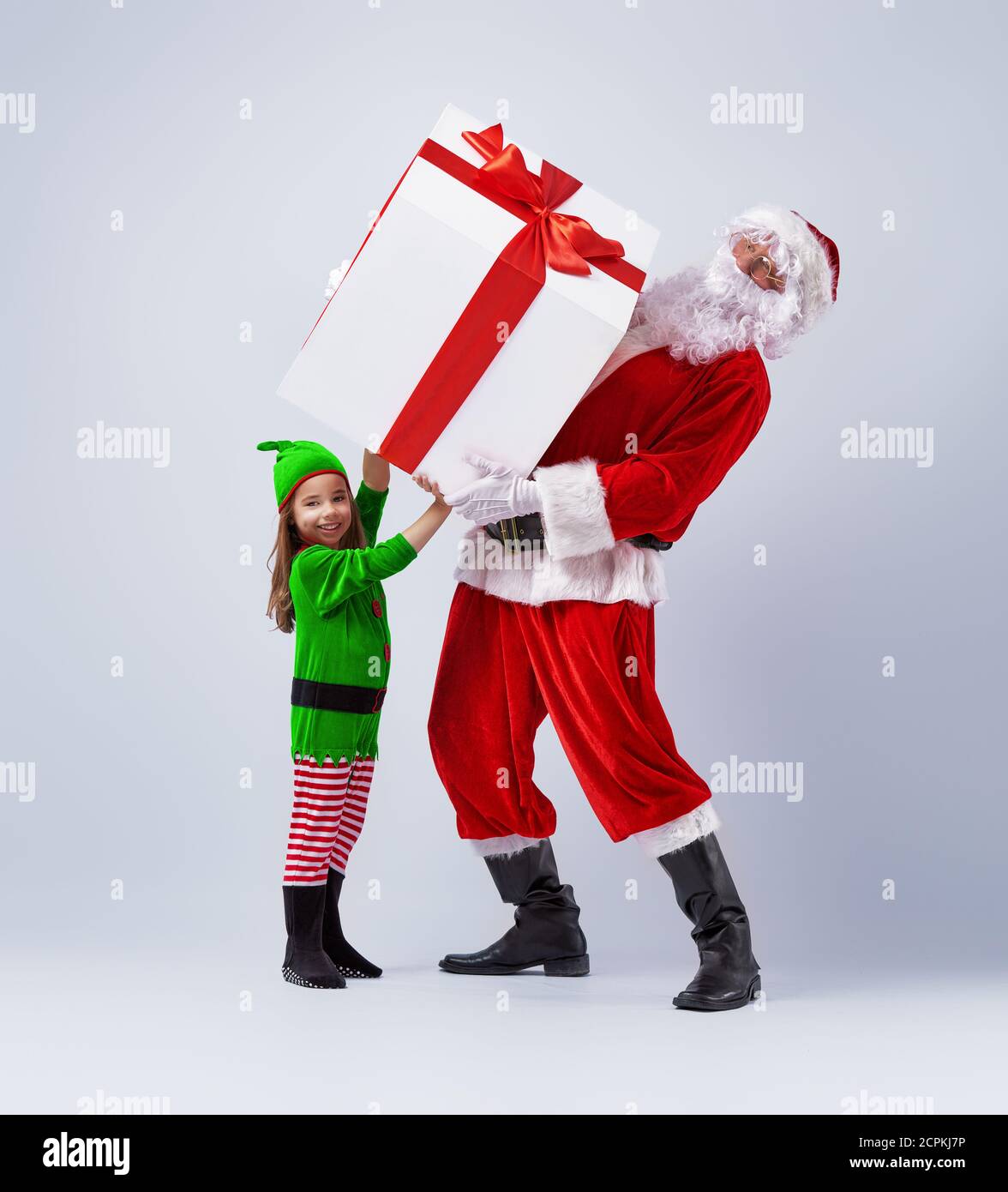 Funny Santa and elf holding together a large Christmas gift Stock Photo ...