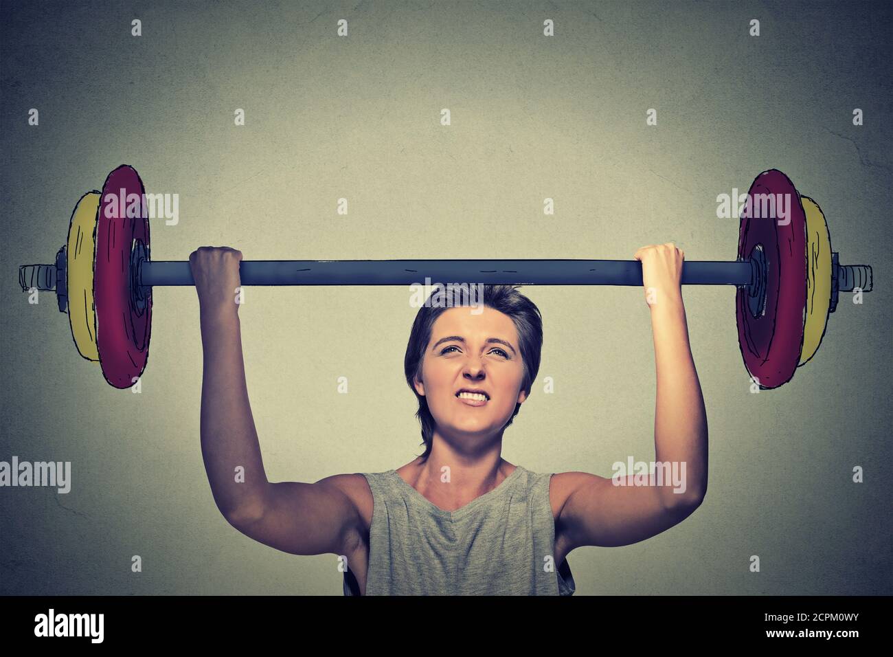 Strong woman lifting heavy barbell isolated on gray wall background ...
