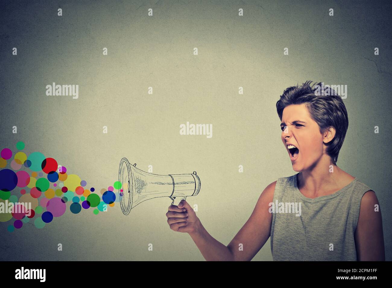 Portrait angry screaming young woman holding megaphone isolated on grey ...