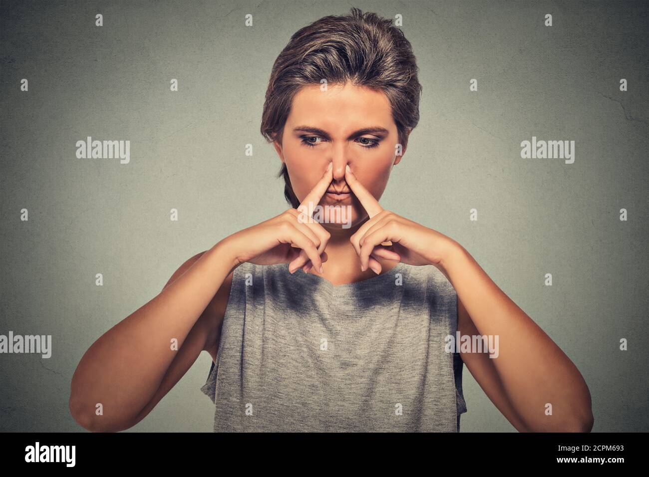 headshot woman pinches nose with fingers hand looks with disgust away ...