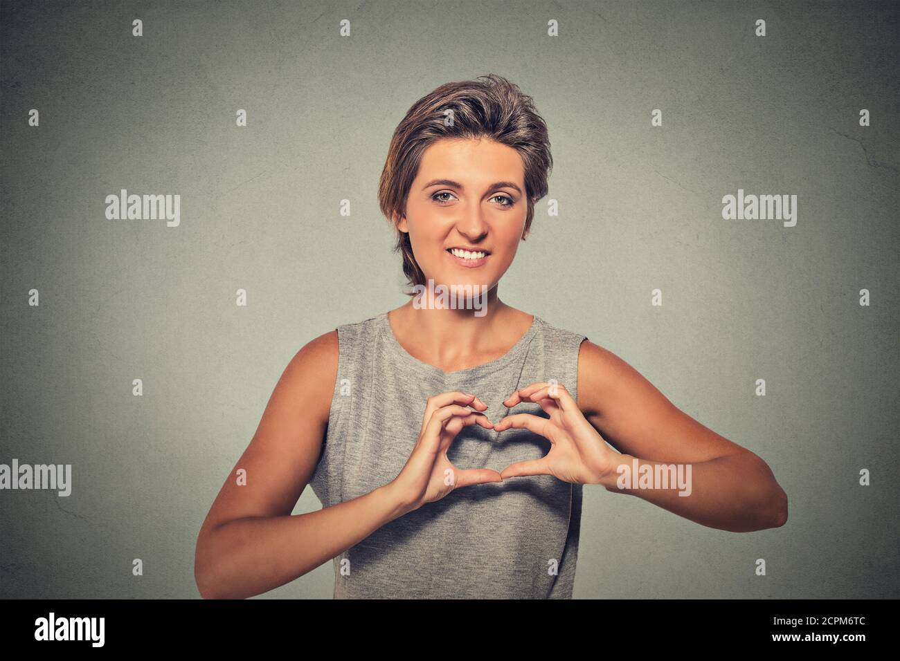 Closeup portrait smiling cheerful happy young woman making heart sign ...