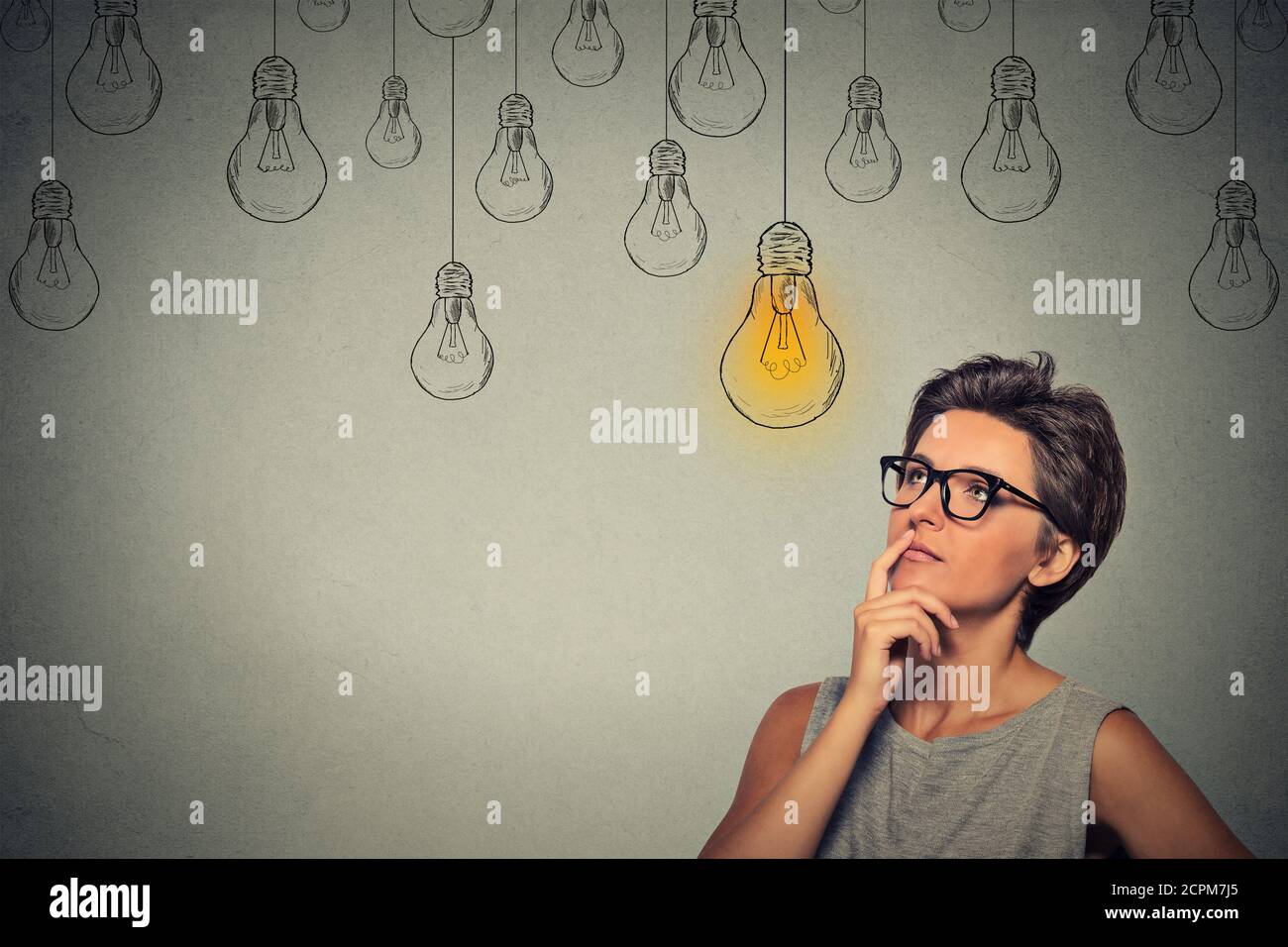 Portrait thinking woman in glasses looking up with light idea bulb ...