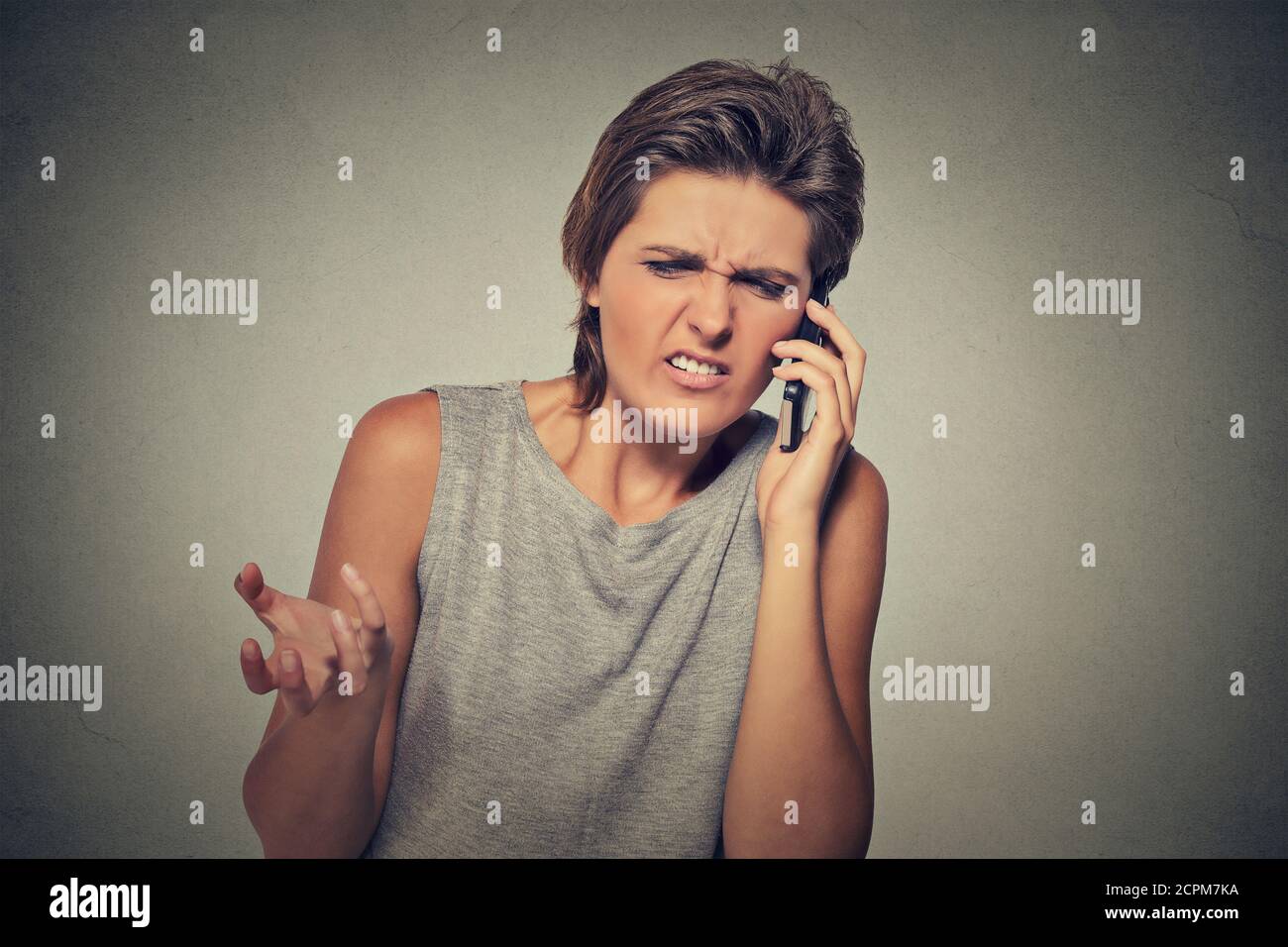 Upset skeptical, unhappy angry woman talking on phone isolated on gray ...
