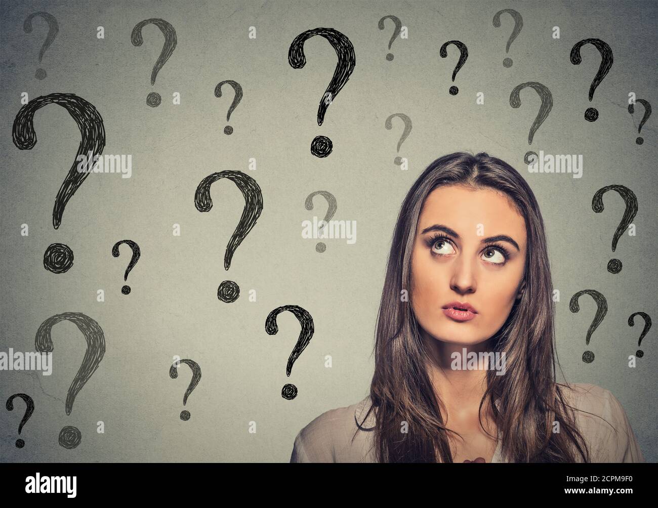 Portrait thinking young business woman looking up at many question ...