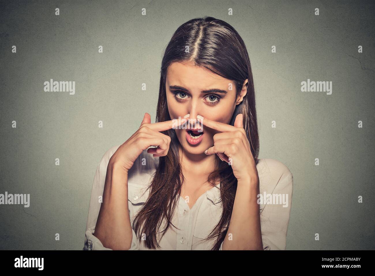 Closeup portrait headshot woman pinches nose with fingers hands looks ...