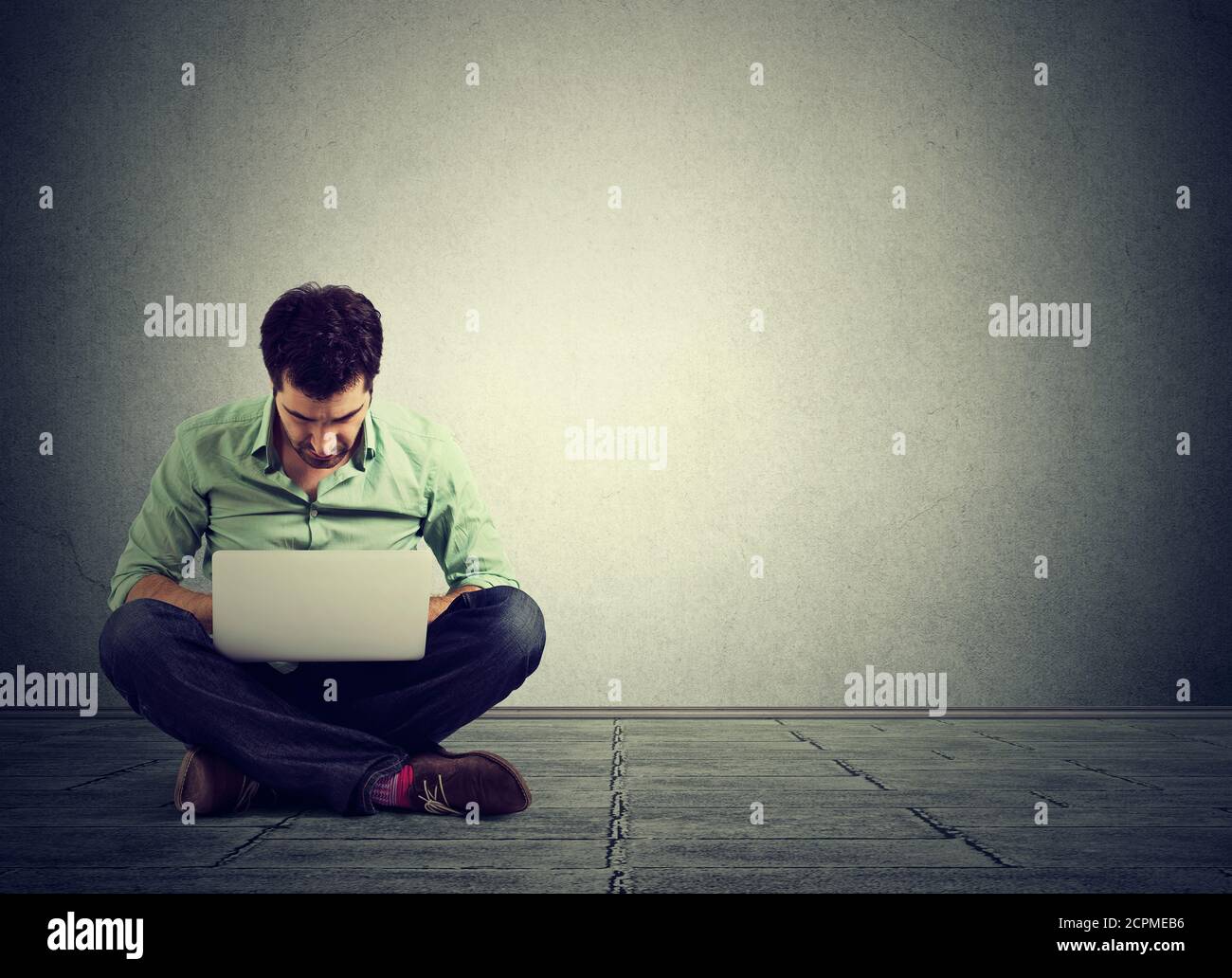 perfect technology. Man sitting on a floor working on laptop computer ...