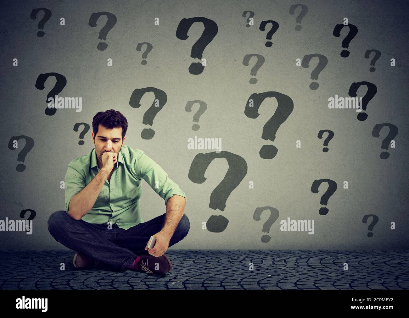 young business man sitting on a floor in front of wall with many ...
