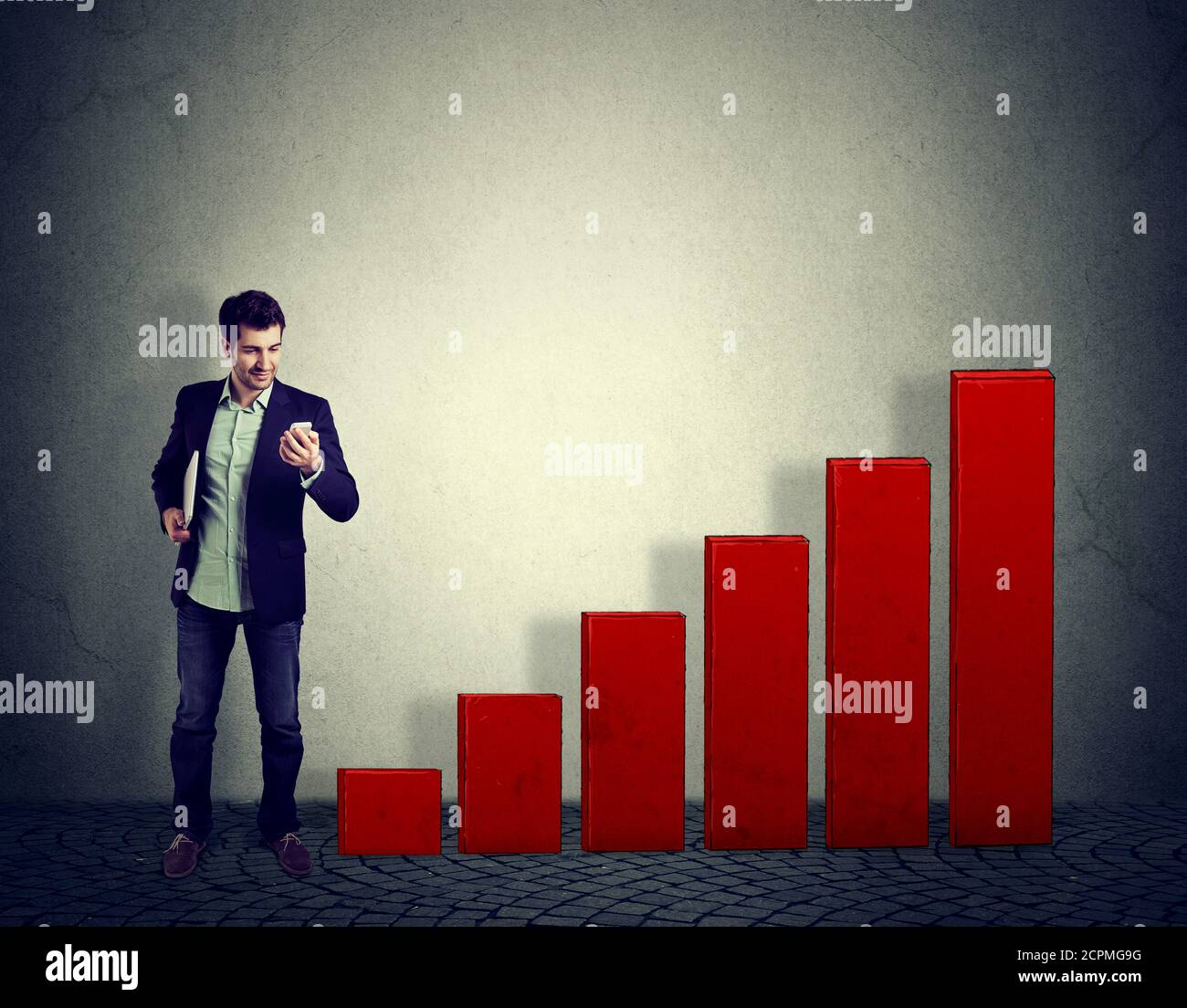 Business man with laptop reading data on mobile phone standing by ...