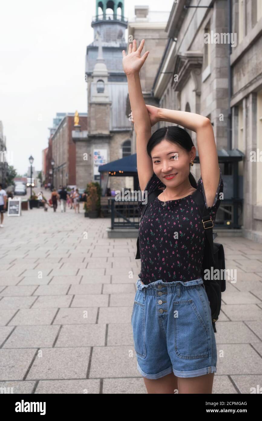 A chinese woman raising her arm and hand on the sidewalk in the city of ...