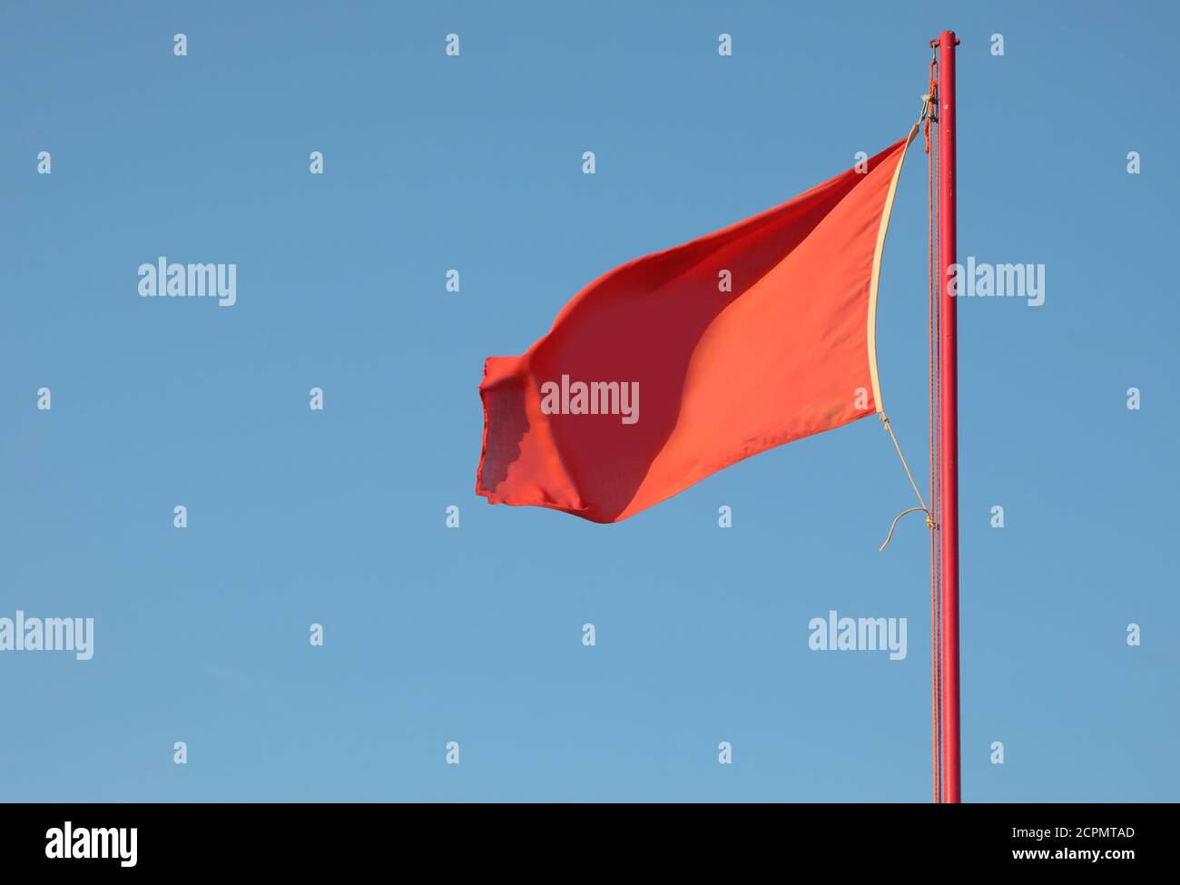 big red flag waving to indicate danger with the background of blue sky ...