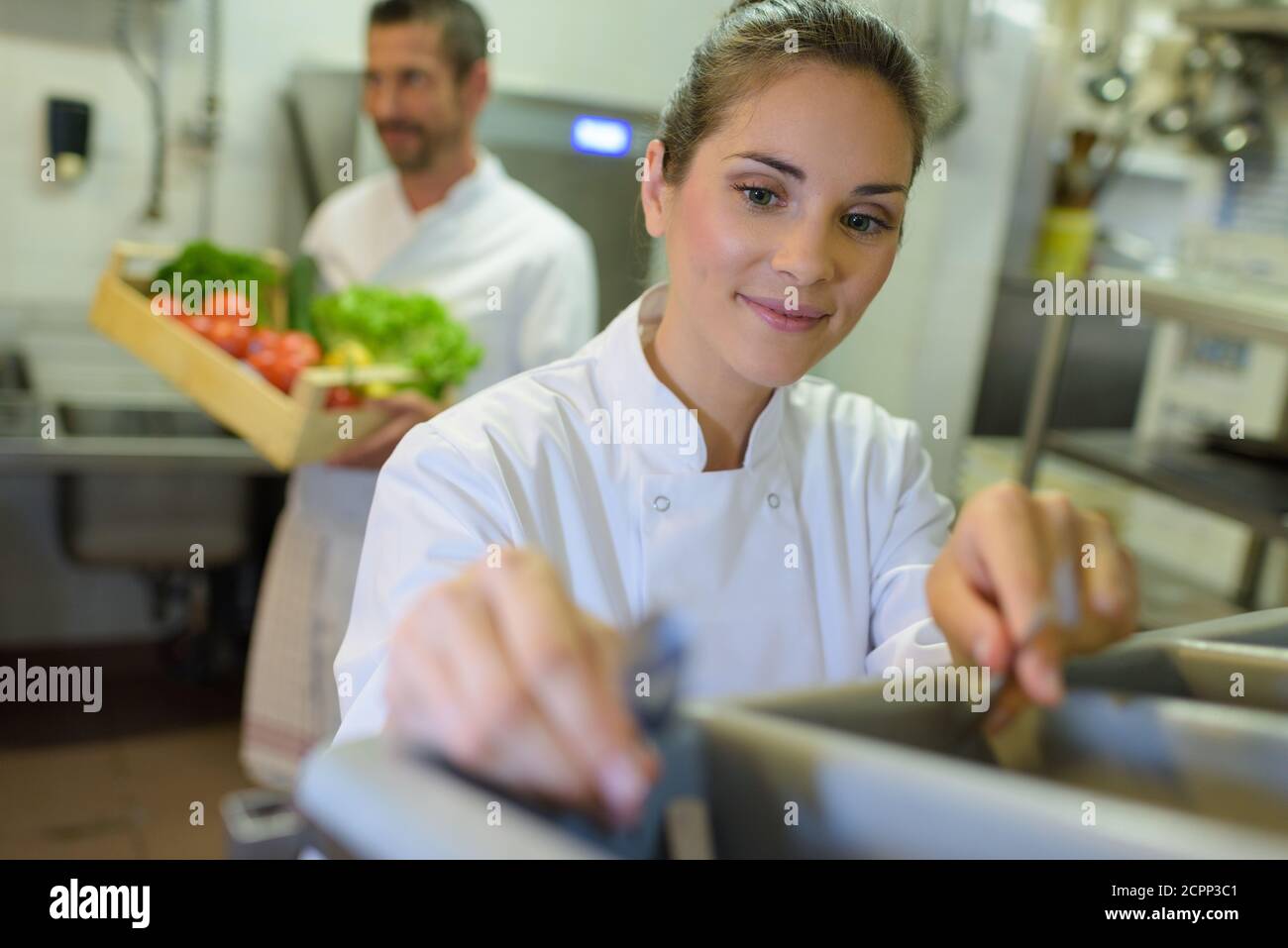 female chef garnishing meal on counter in commercial kitchen Stock ...