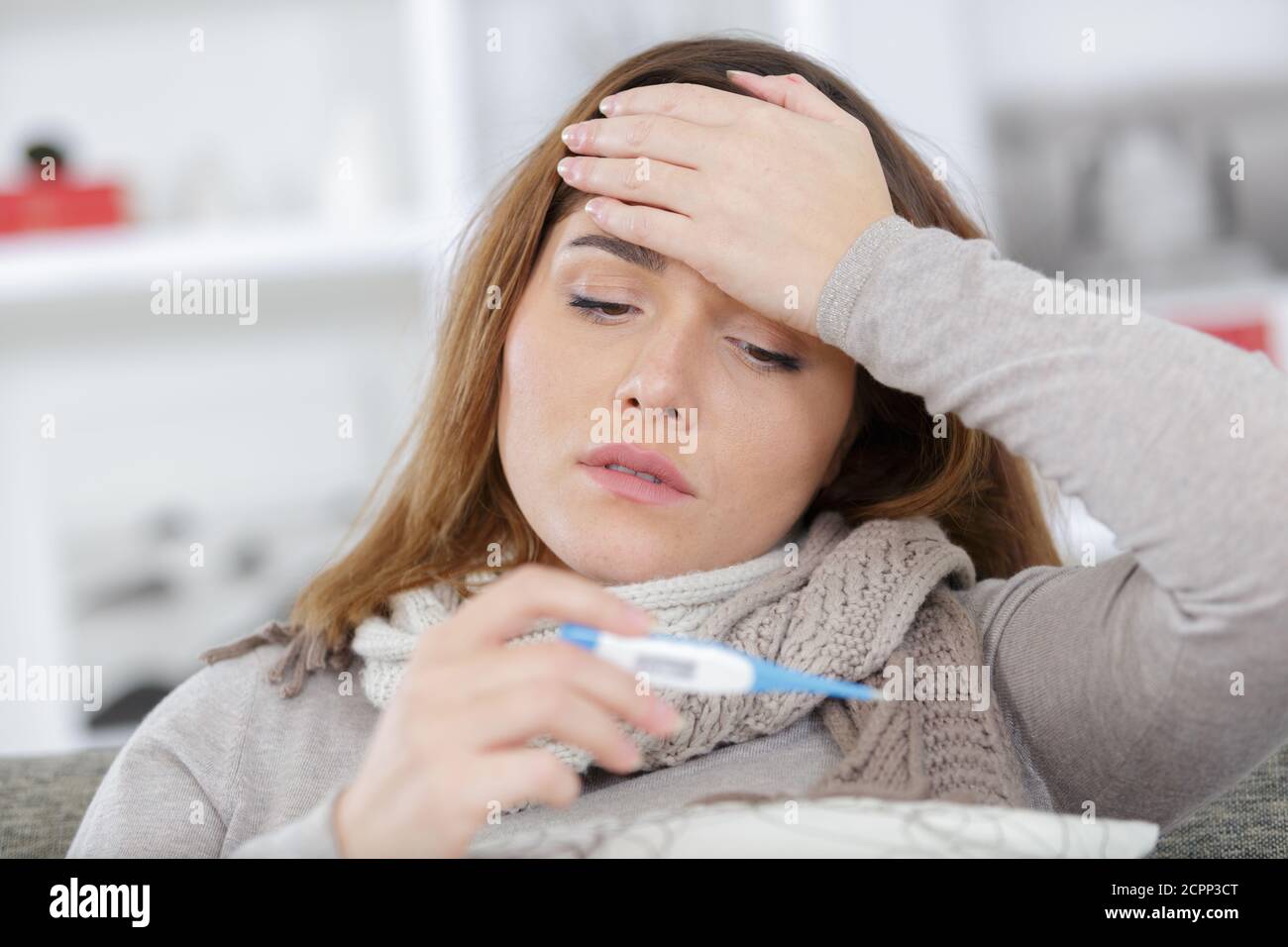 a sick woman looking at thermometer Stock Photo - Alamy