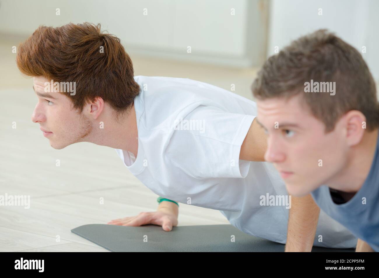 young men doing planking while watching movie on tablet Stock Photo - Alamy
