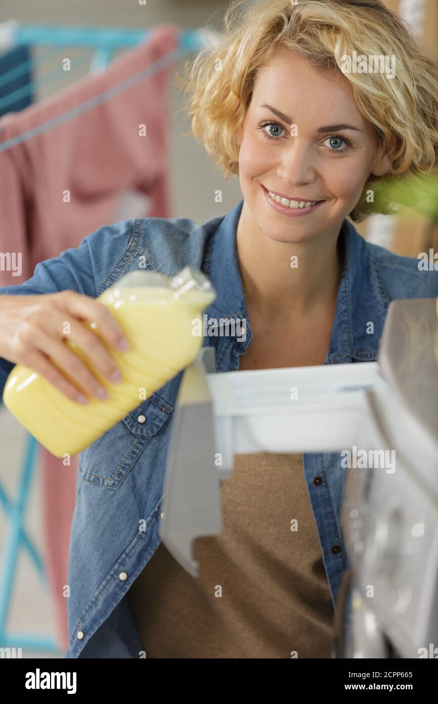 happy woman pours rinsing liquid into the washing machine Stock Photo ...