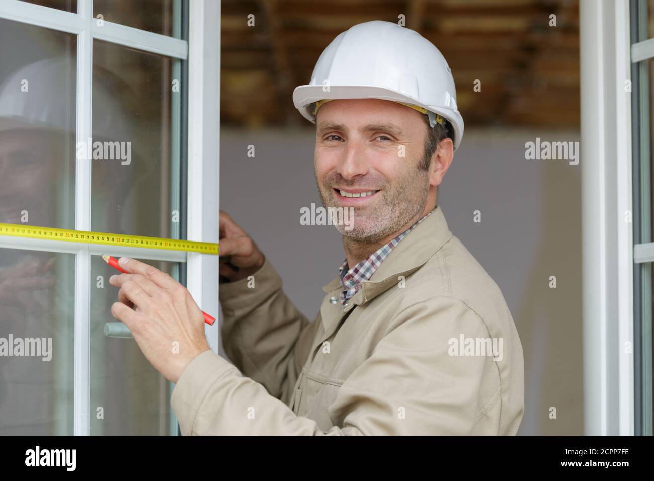 builder measuring a window using a tape measure and pencil Stock Photo ...