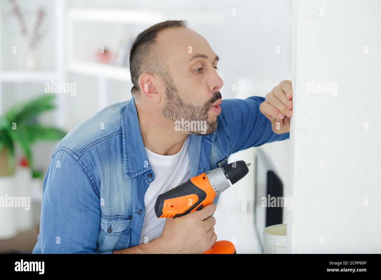 man blowing dust from screw hole Stock Photo - Alamy
