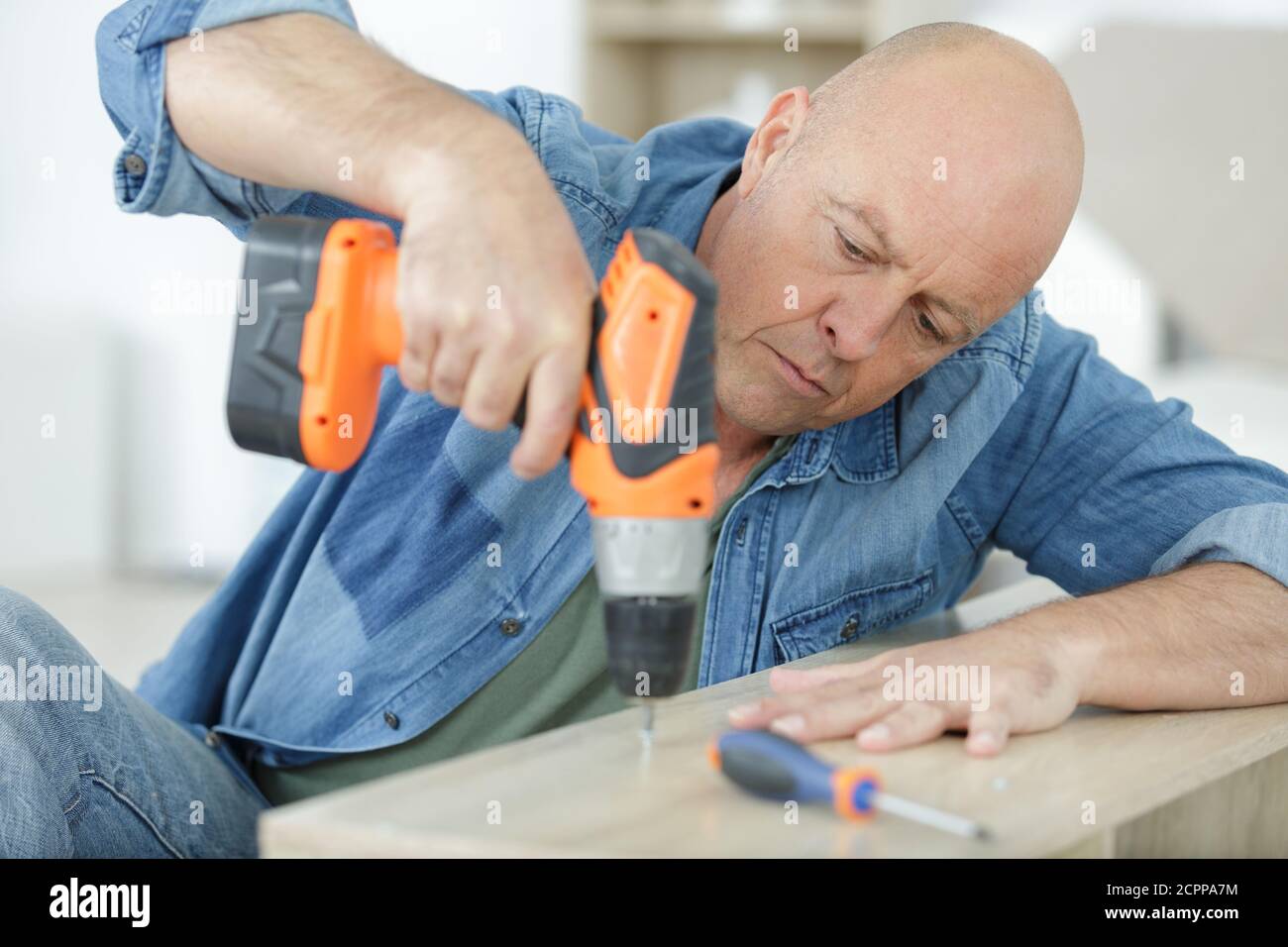 mature man using electric screwdriver while fixing a furniture Stock ...