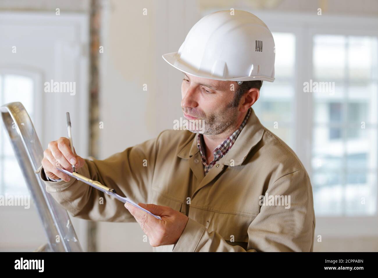 male builder writing on clipboard Stock Photo - Alamy