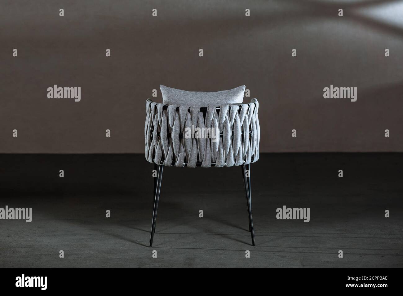 Closeup of a small comfortable chair with a gray cushion on it in a ...