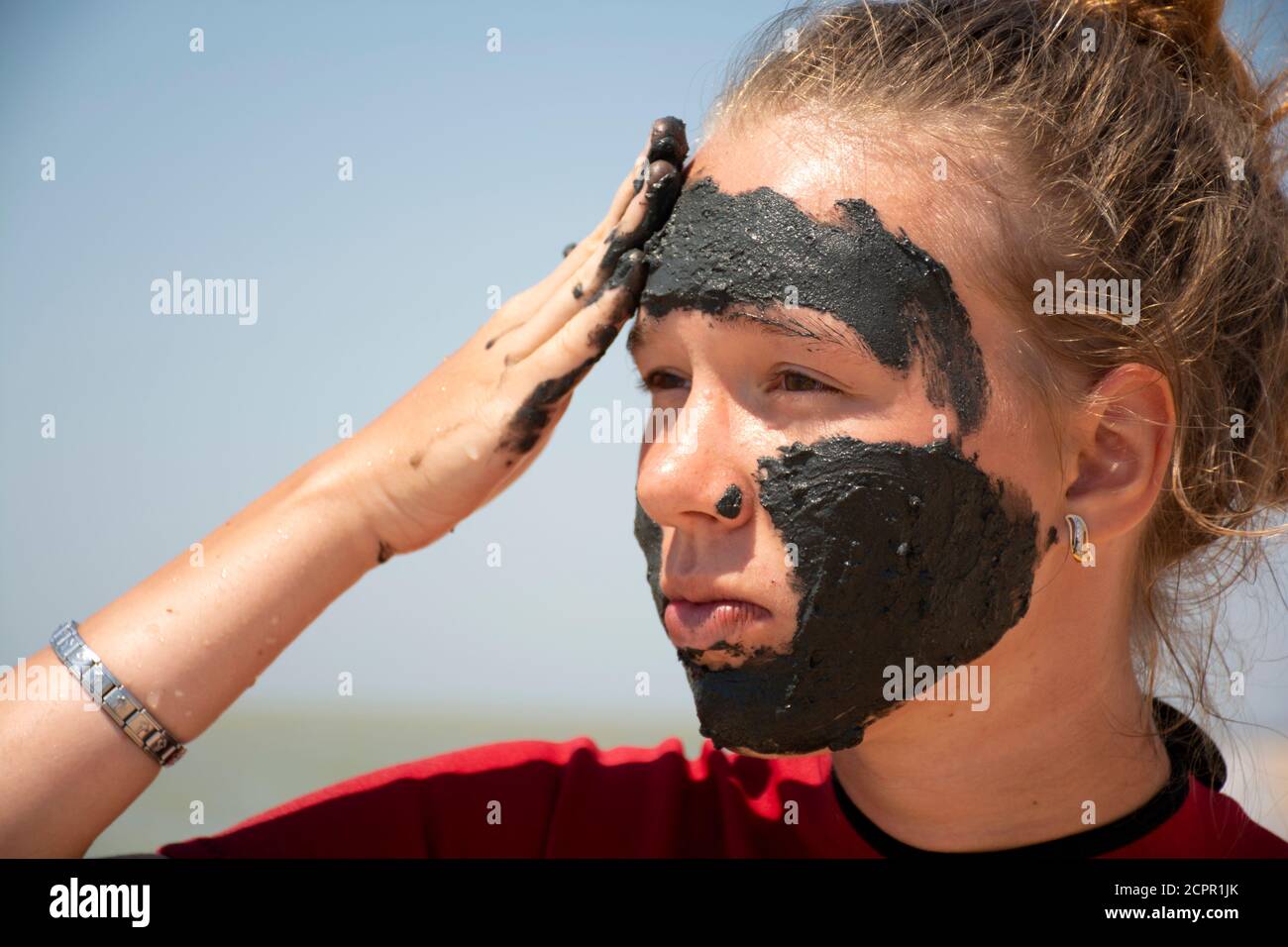 Young beautiful girl with a gray magnetic mud mask on her face on a ...