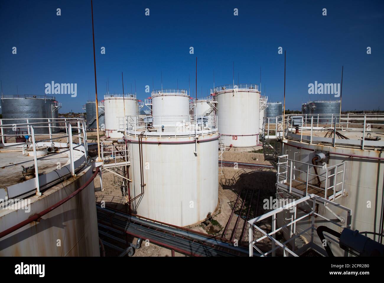 White oil storage tanks of oil refinery plant in desert under bright ...