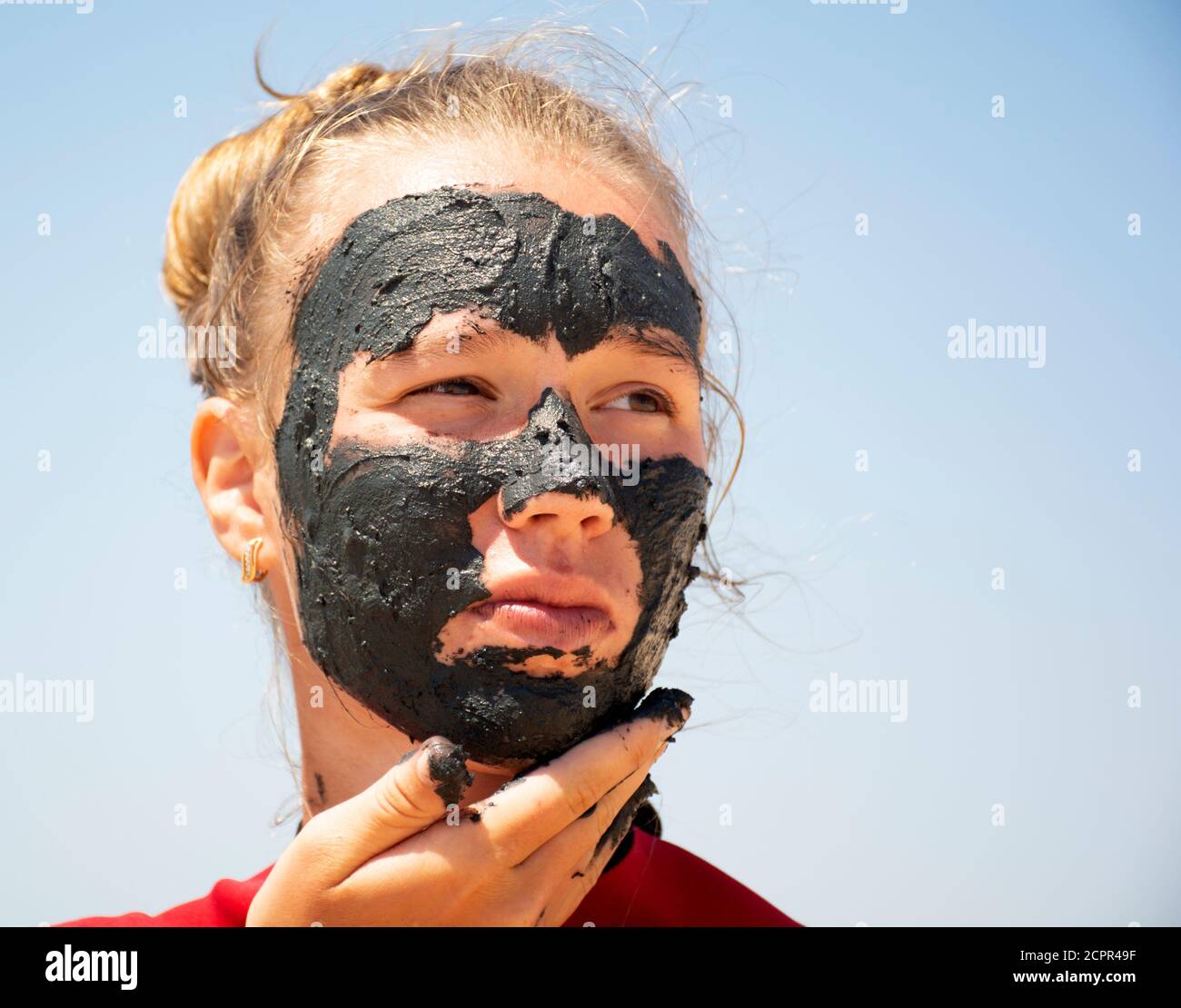 Young beautiful girl with a gray magnetic mud mask on her face on a ...
