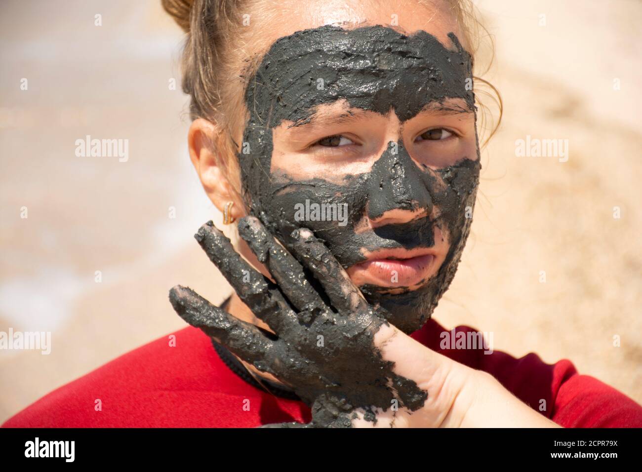 Young beautiful girl with a gray magnetic mud mask on her face on a ...