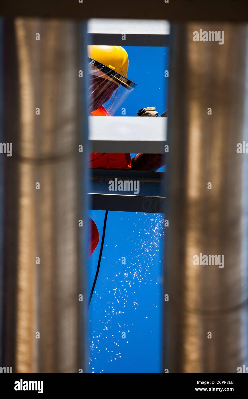 Worker in yellow helmet with angle grinder, glass protective mask and ...