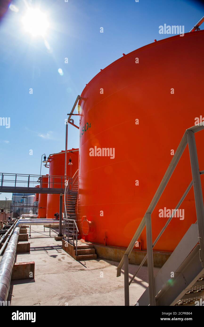 Orange steel storage tanks with acid and metal stairway on sulfuric ...