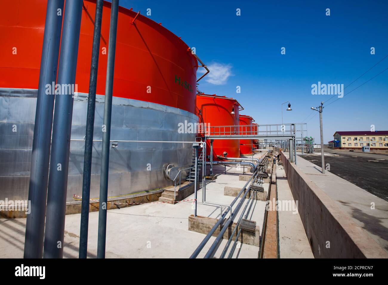 Orange steel storage tanks with acid on sulfuric acid plant warehouse ...
