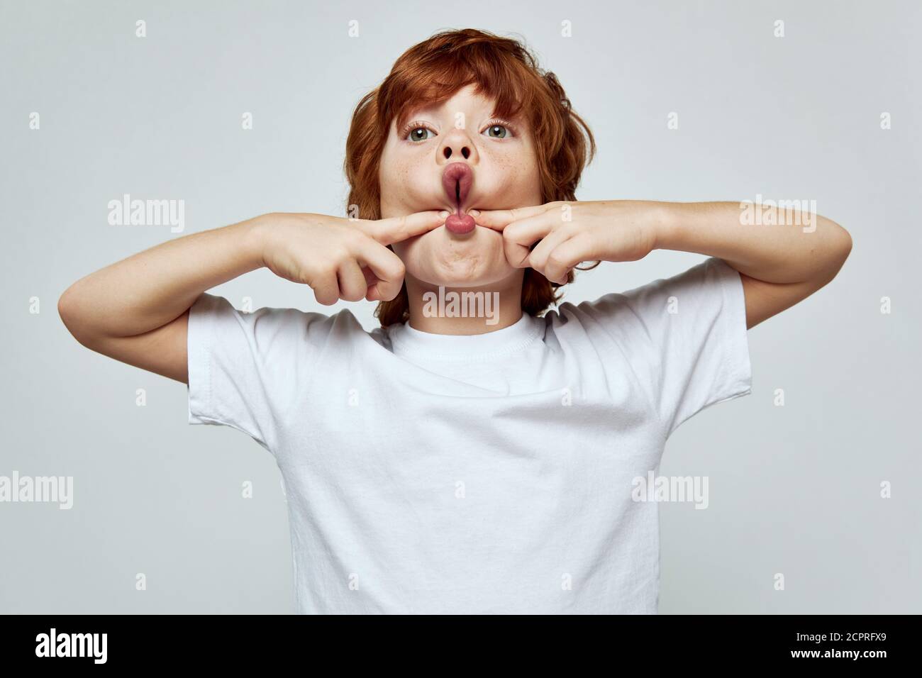 grimacing redhead boy open mouth squeezing cheeks studio cropped Stock ...